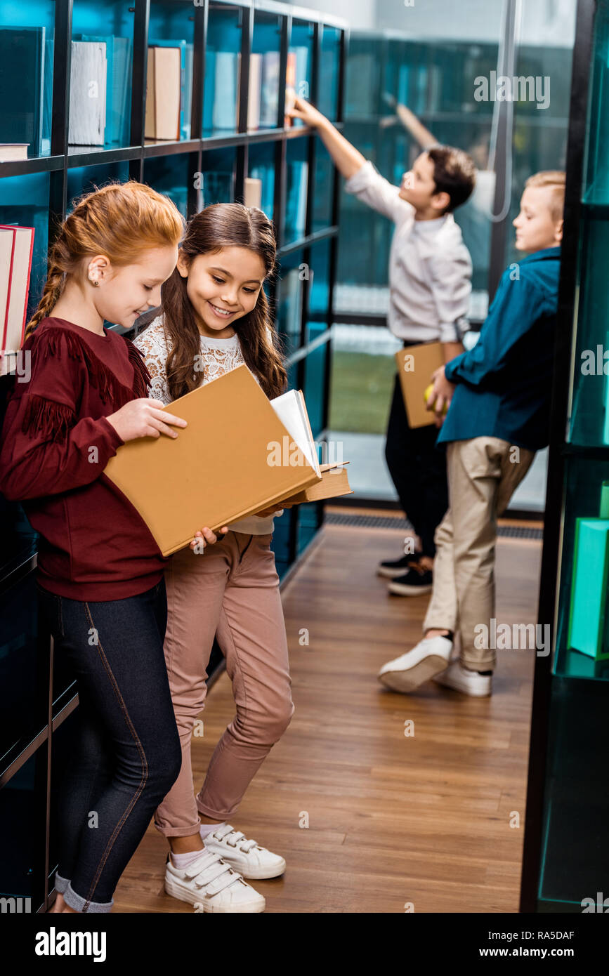 adorable smiling schoolkids reading book in library Stock Photo - Alamy