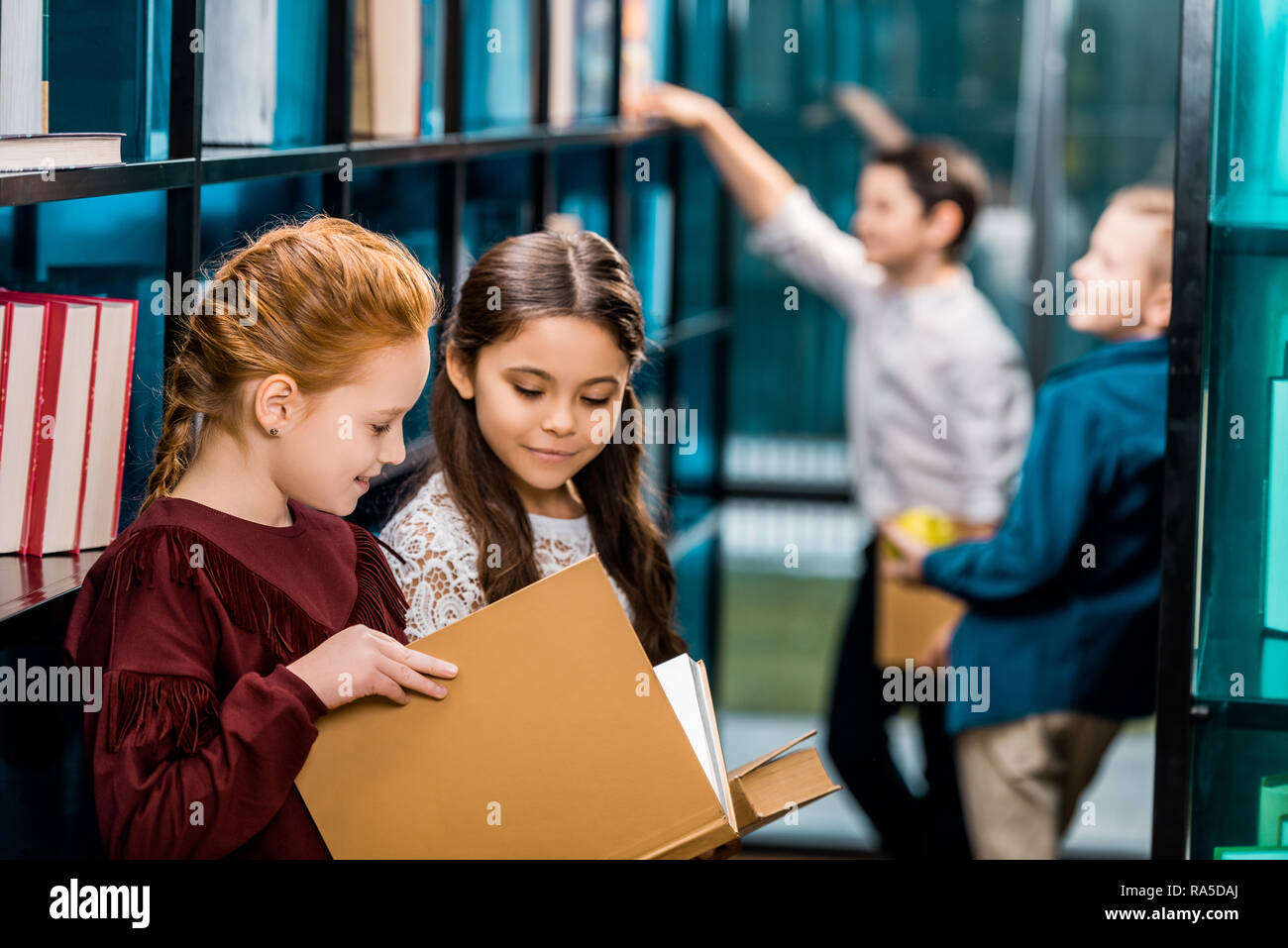 beautiful smiling schoolchildren reading books in library Stock Photo ...