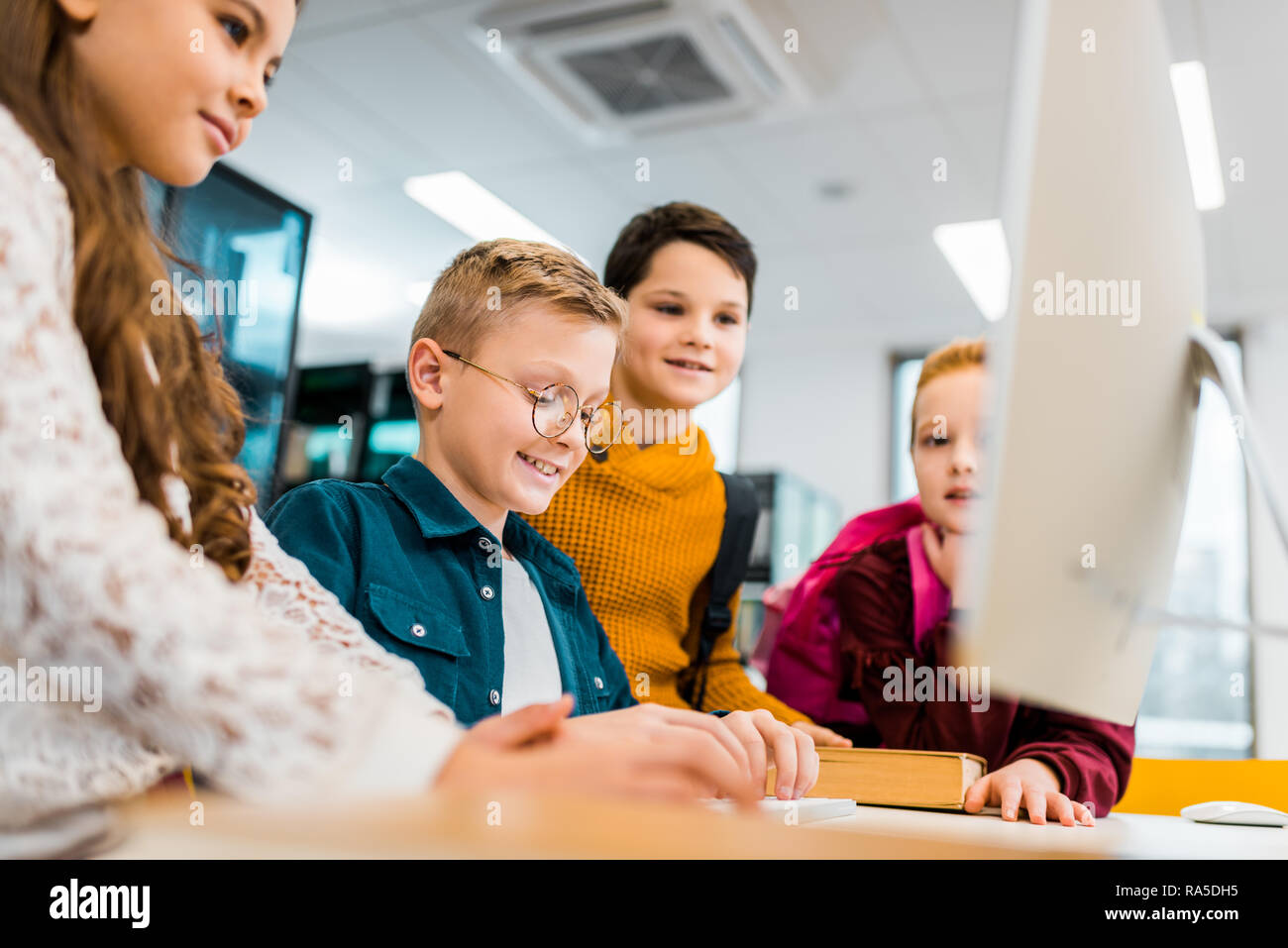 adorable smiling schoolkids using desktop computer in library Stock ...