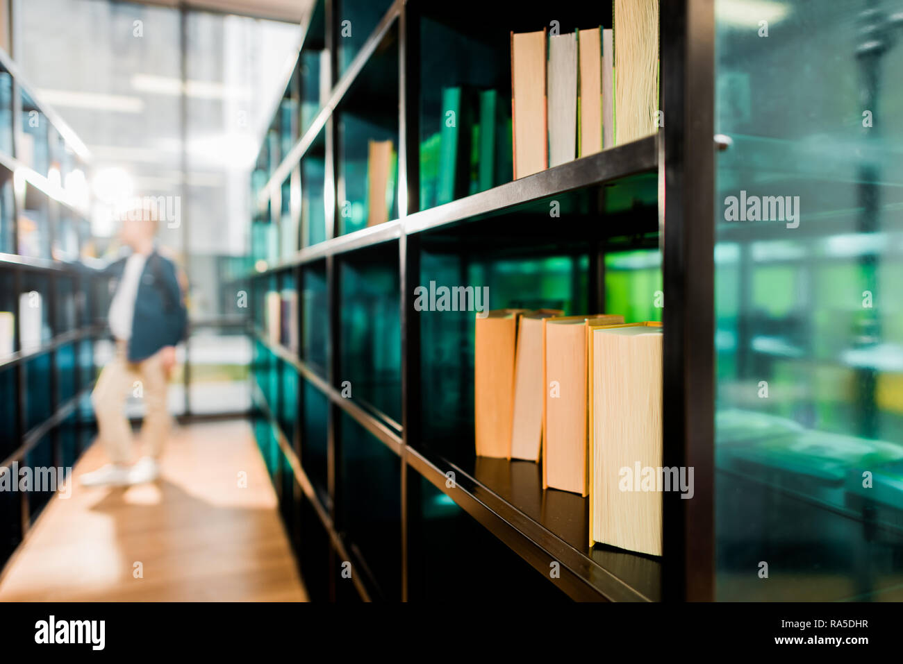 books on bookshelves and schoolboy standing behind in library Stock ...