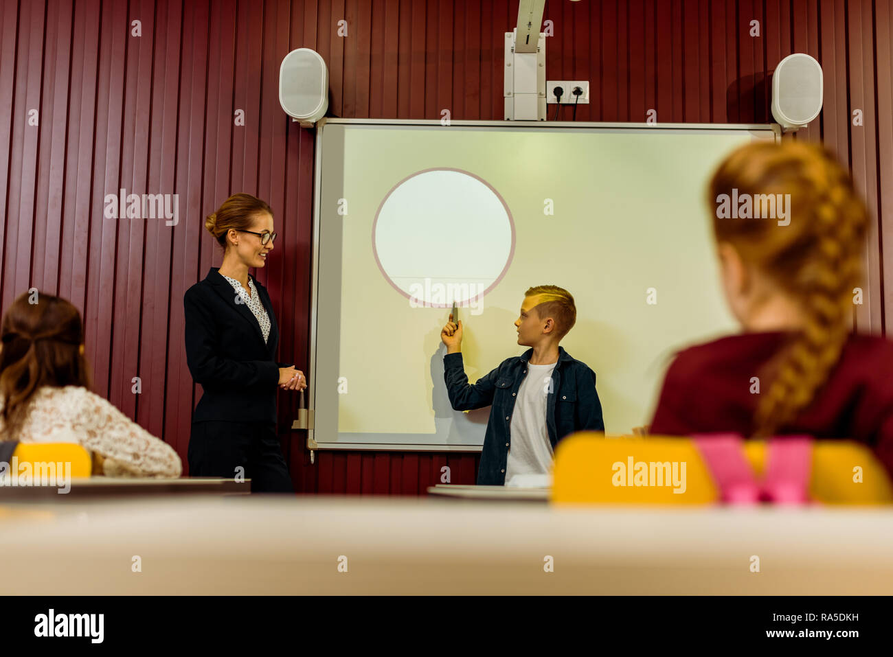 teacher and schoolkids looking at boy making presentation at ...