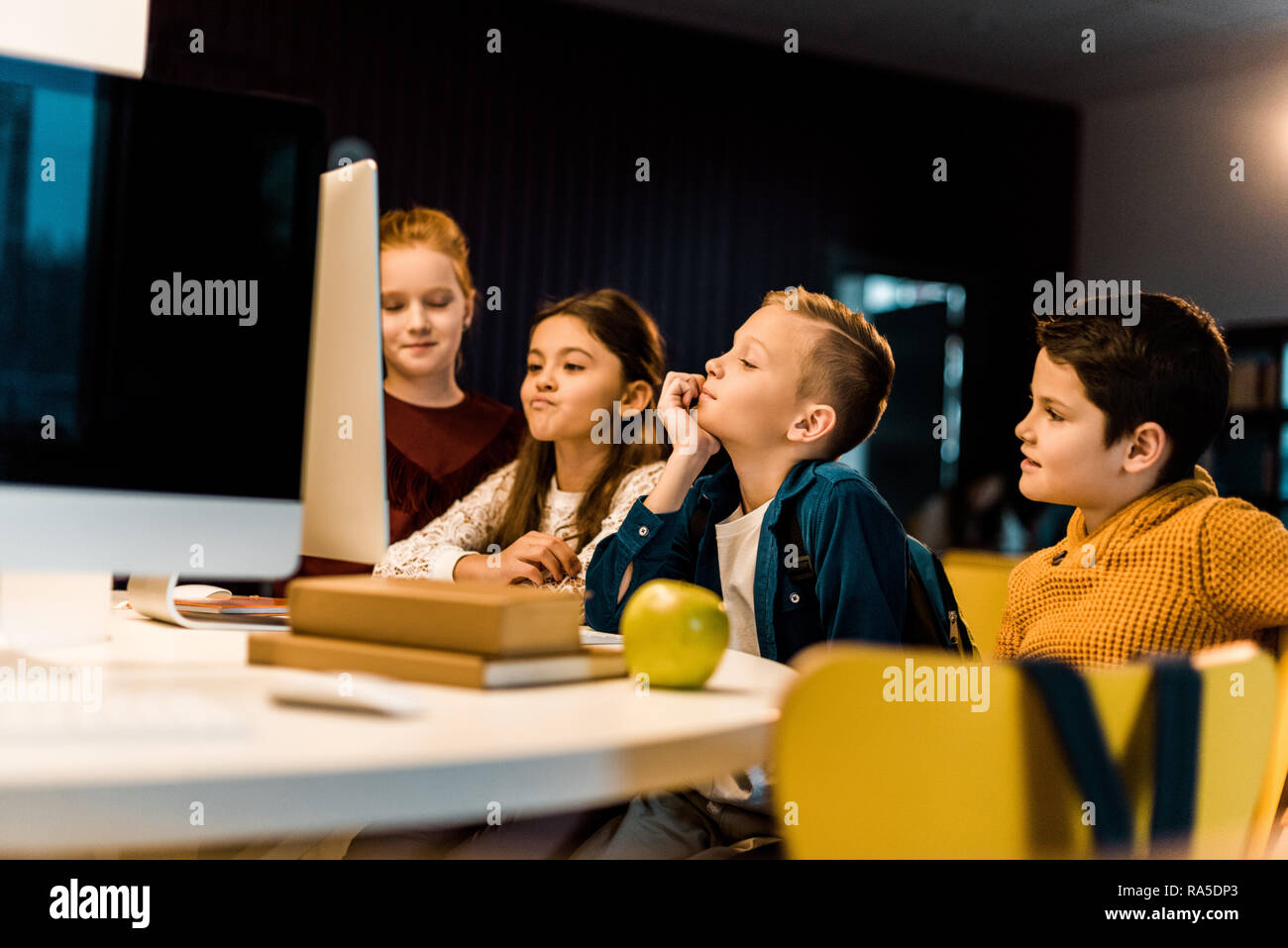 adorable schoolchildren using desktop computer in modern library Stock ...
