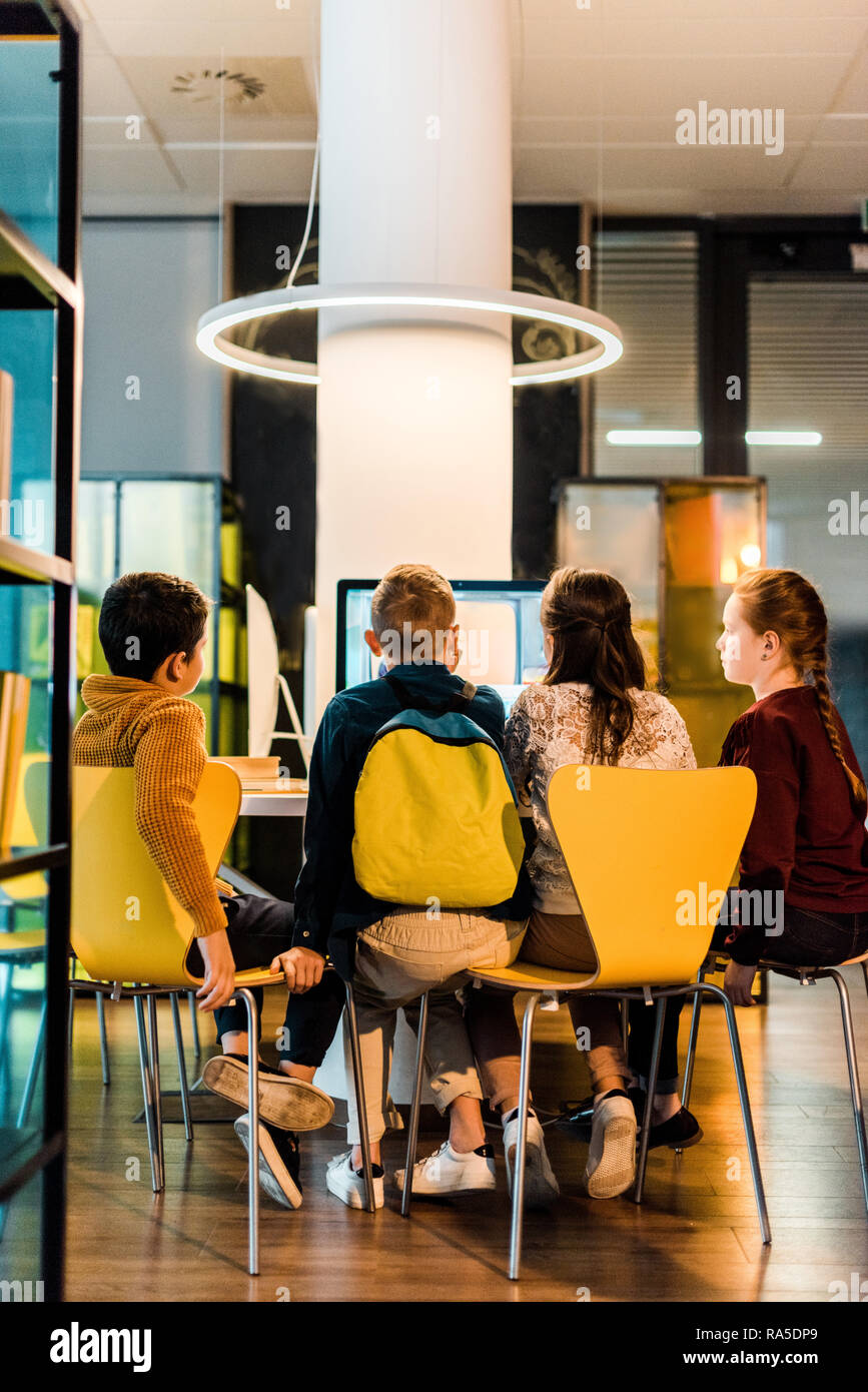 back view of four schoolkids using computers in modern library Stock ...