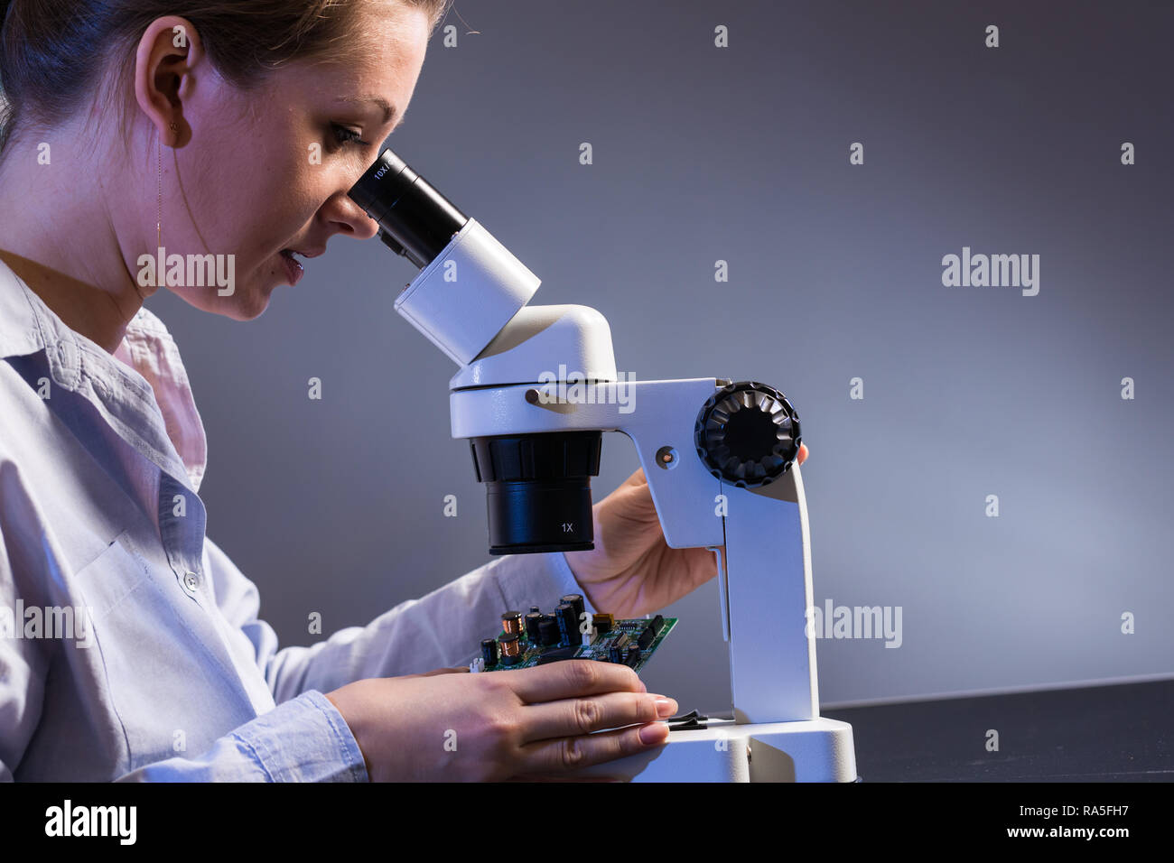 young woman computer technician testing a printed circuit board with a ...