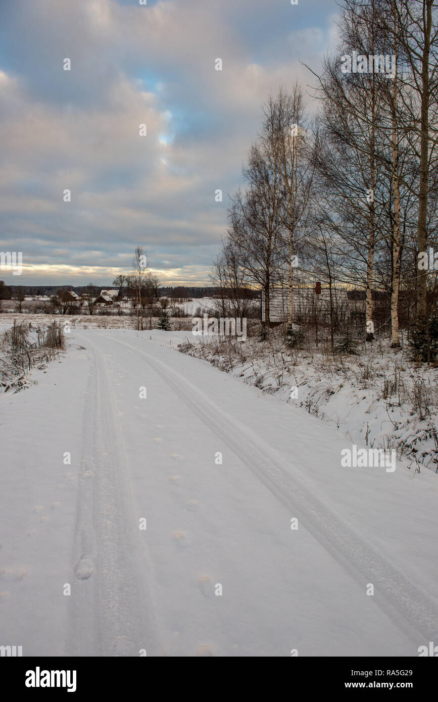 snow covered winter road with tire tracks in perspective with blue sky ...