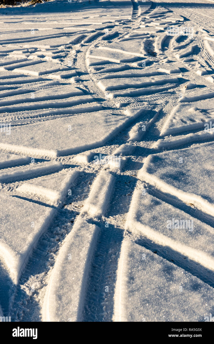 snow covered winter road with tire tracks in perspective with blue sky ...