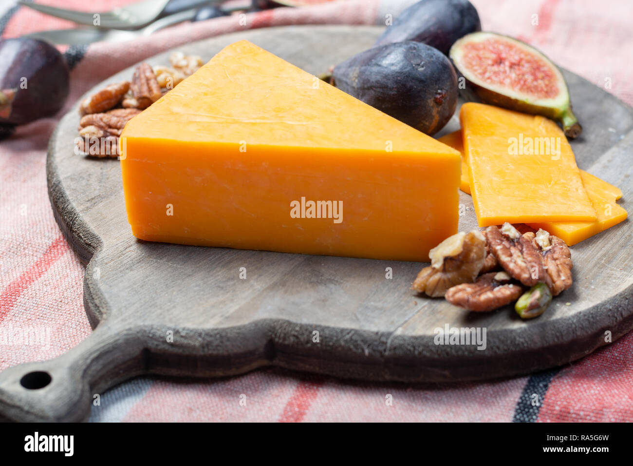 Piece of hard orange Cheddar cheese served with nuts and fresh ripe ...