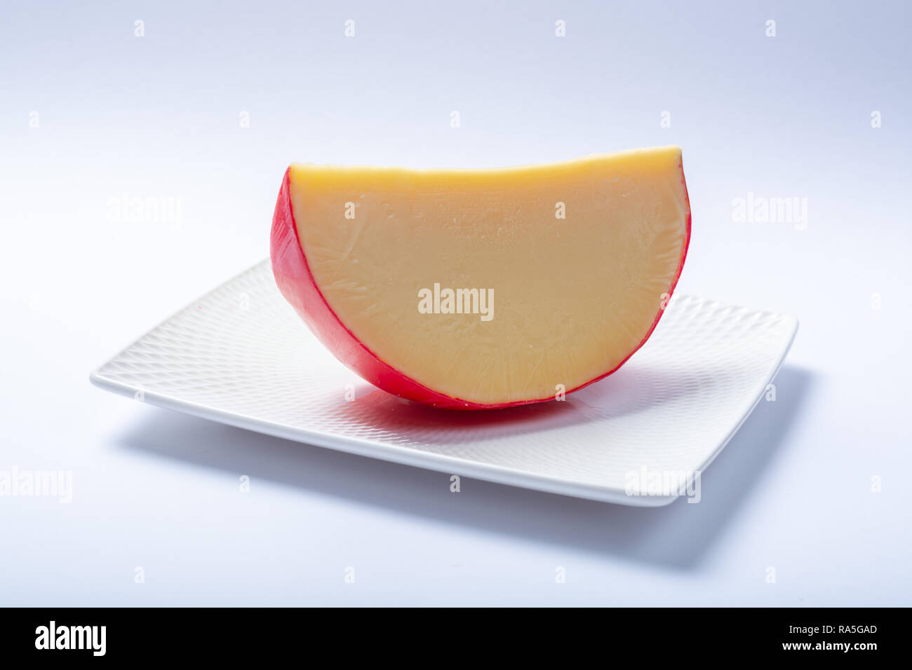 One piece of traditional Dutch red ball Edam cheese close up on white ...