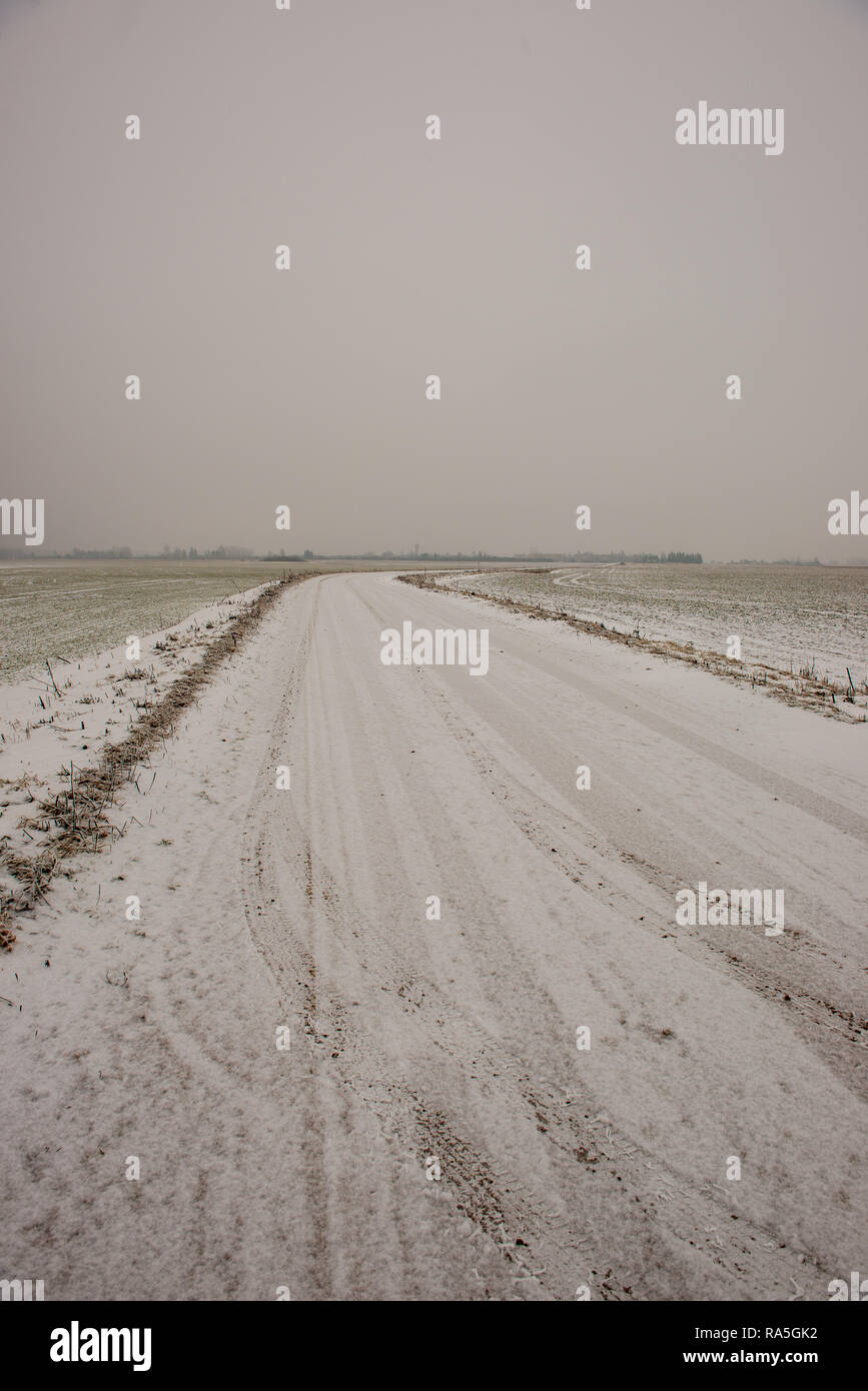 snow covered winter road with tire tracks in perspective with blue sky ...