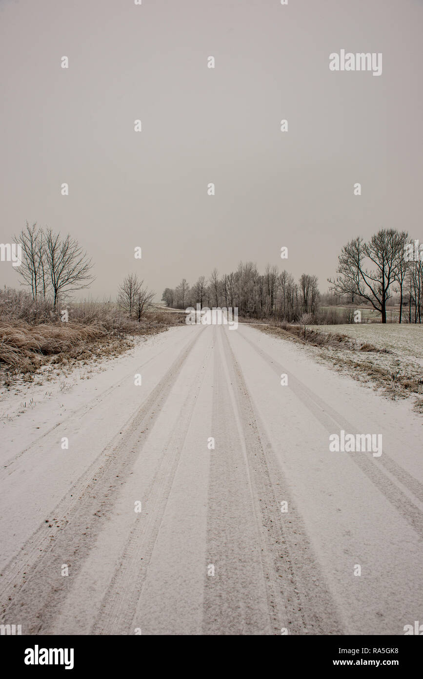 snow covered winter road with tire tracks in perspective with blue sky ...