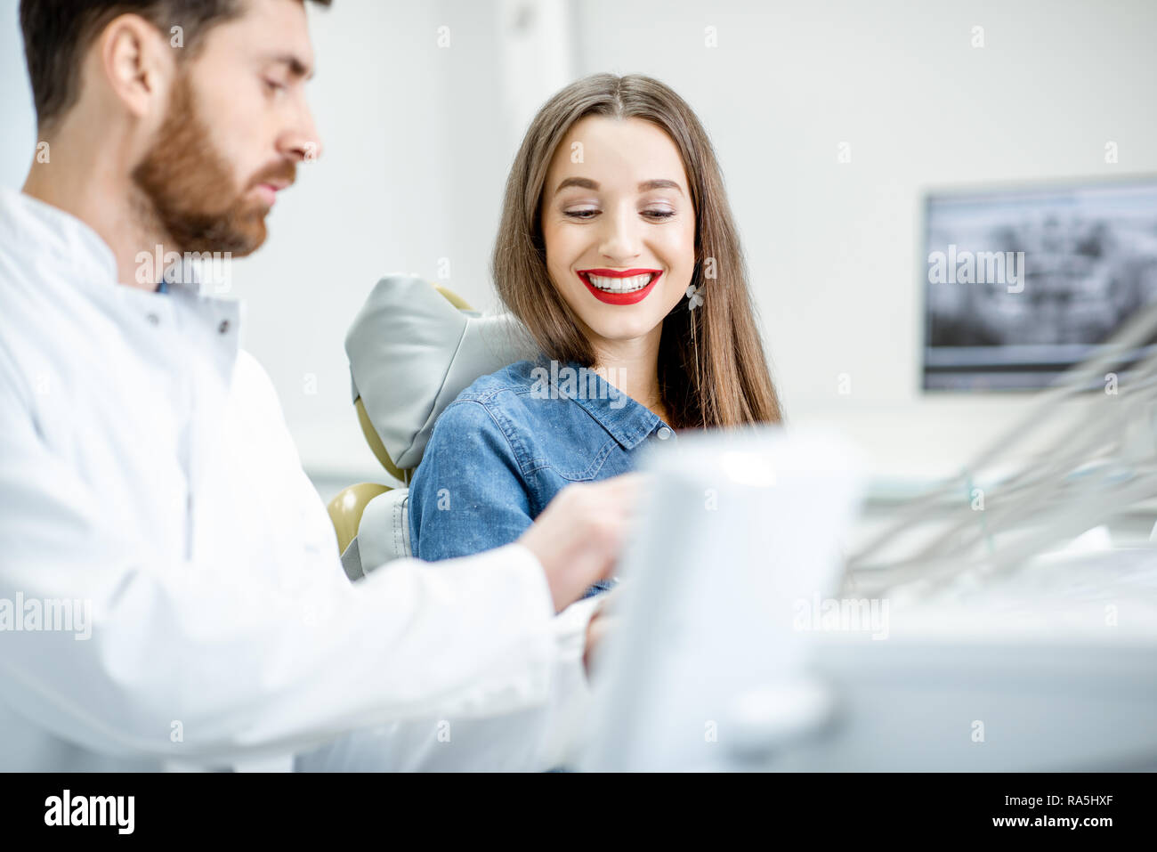 Young beautiful woman during the medical consultation with male dentist in the dental office ...