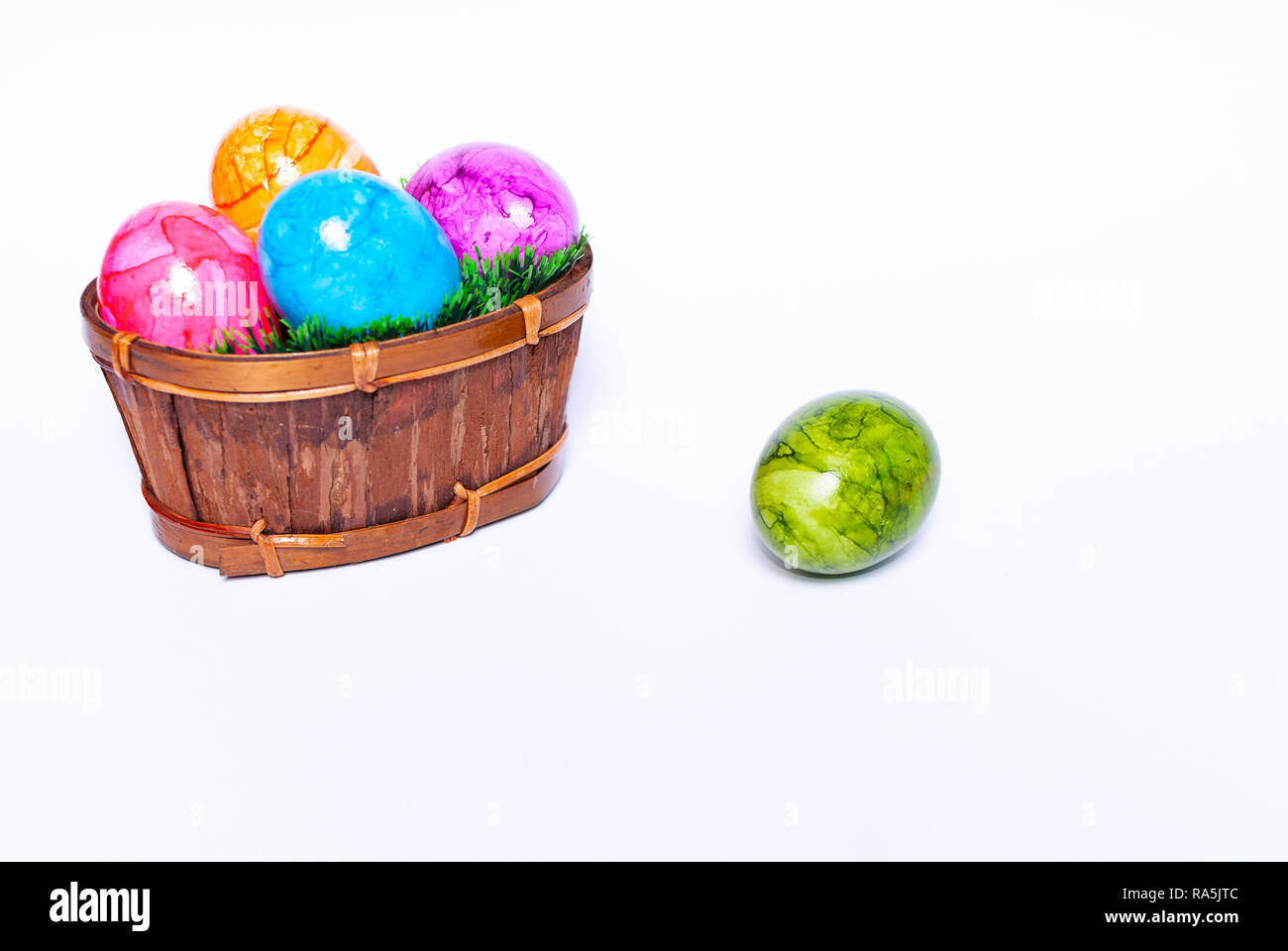 A basket filled with green grass and colorful easter eggs and an extra ...