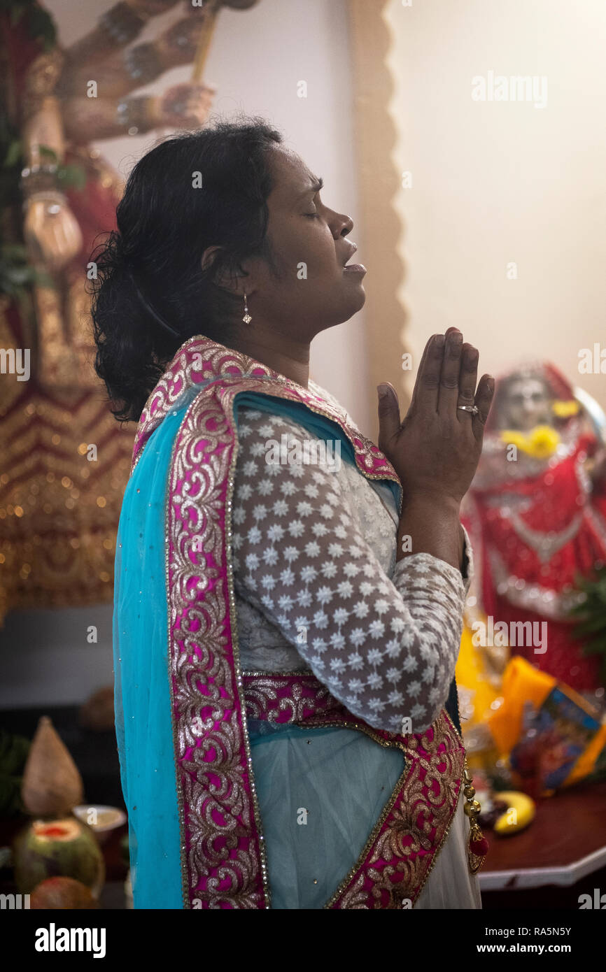 Profile of a devout Hindu woman and priest praying with her hands ...