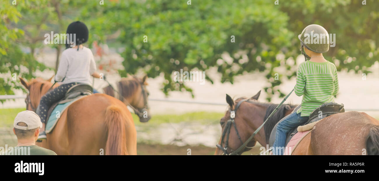 Kids learn to ride a horse near the river before sunset Stock Photo - Alamy