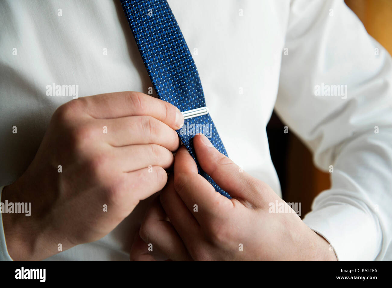 man putting on cuff-links as he gets dressed in formal wear .Groom's ...