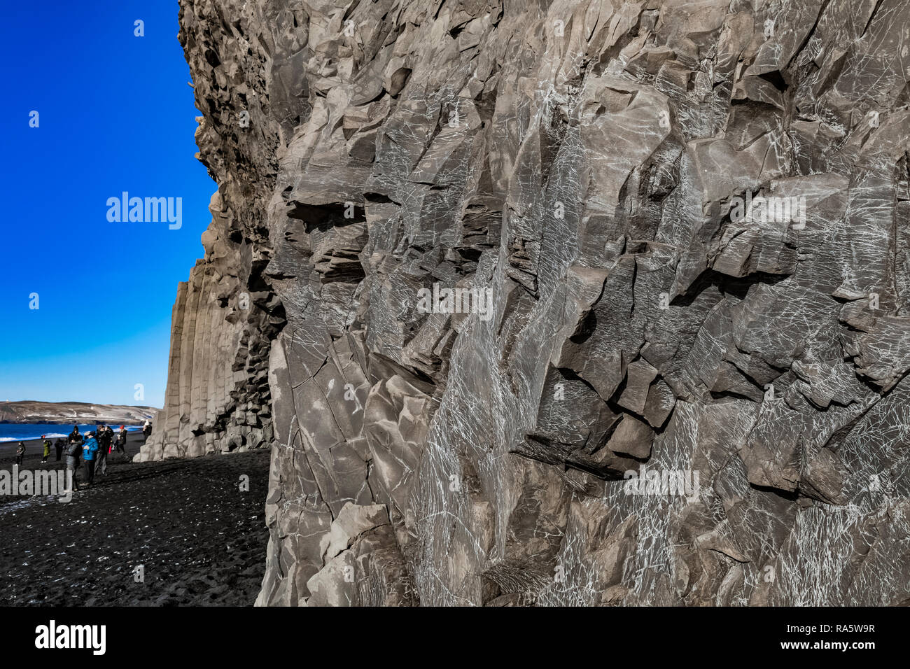 Tourists enjoying the columnar basalt formations along Reynisfjara ...