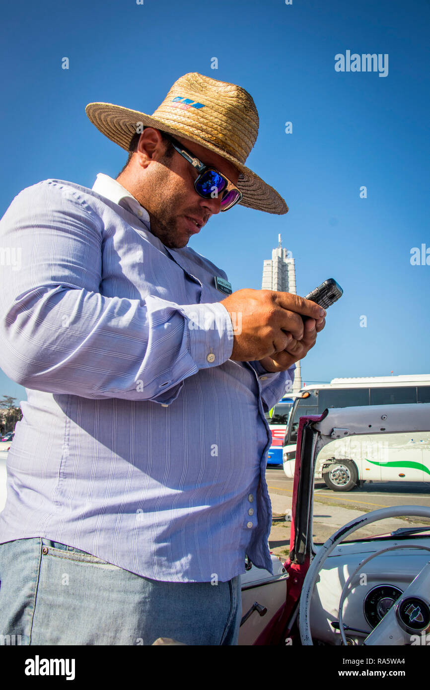 Cuban taxi driver checks his phone in Revolution square havana cuba ...