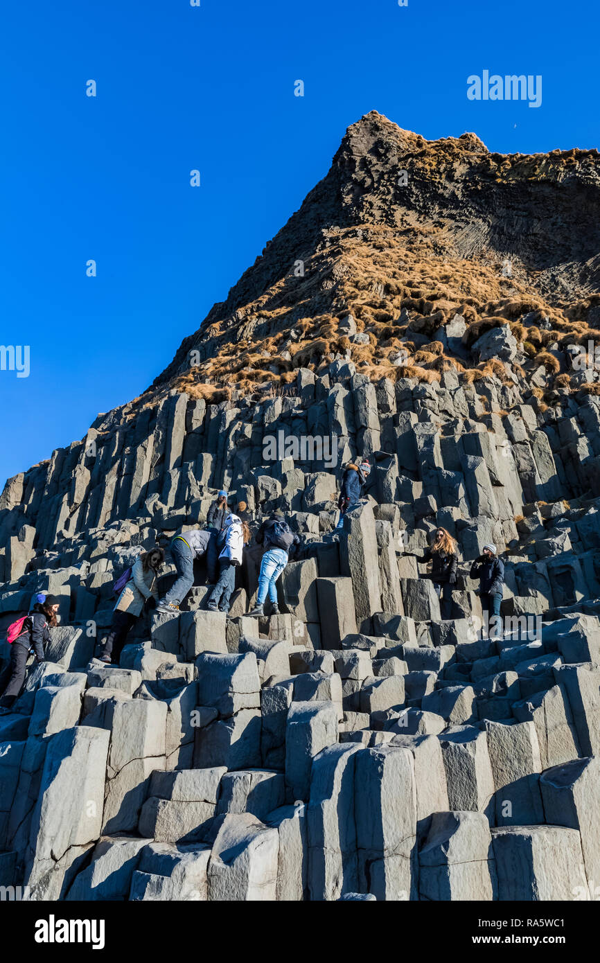 Tourists climbing on columnar basalt formations along Reynisfjara Black ...