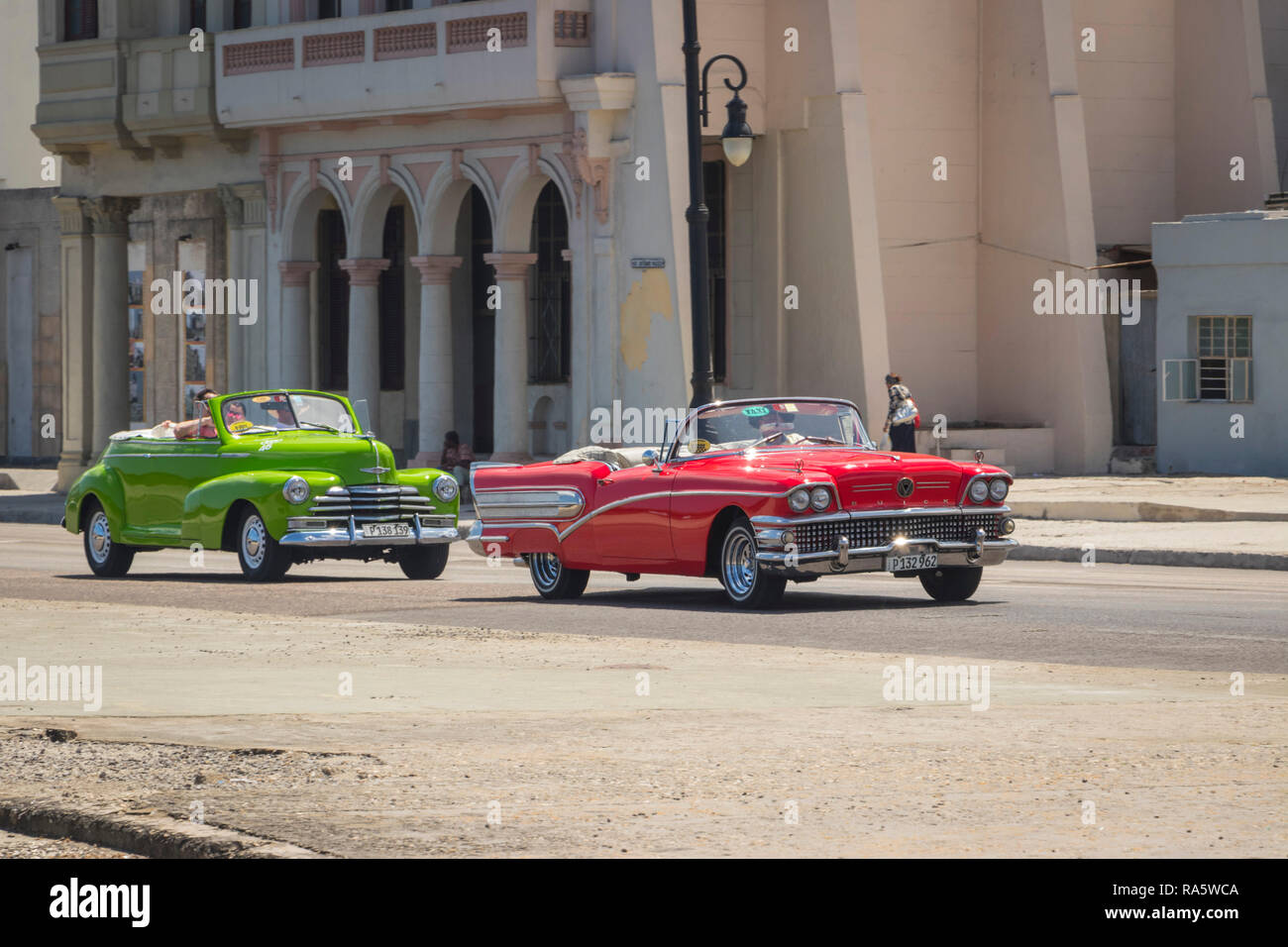 two classic vintage American cars driving in Havana, Cuba, Caribbean ...