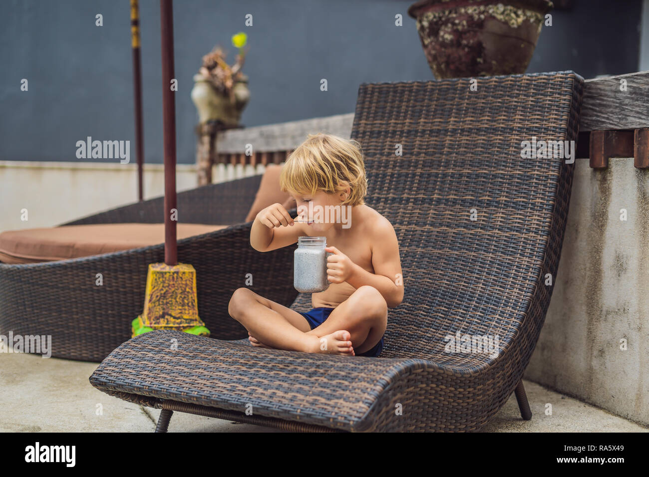 The boy eats chia pudding in the morning by the pool. Healthy breakfast ...