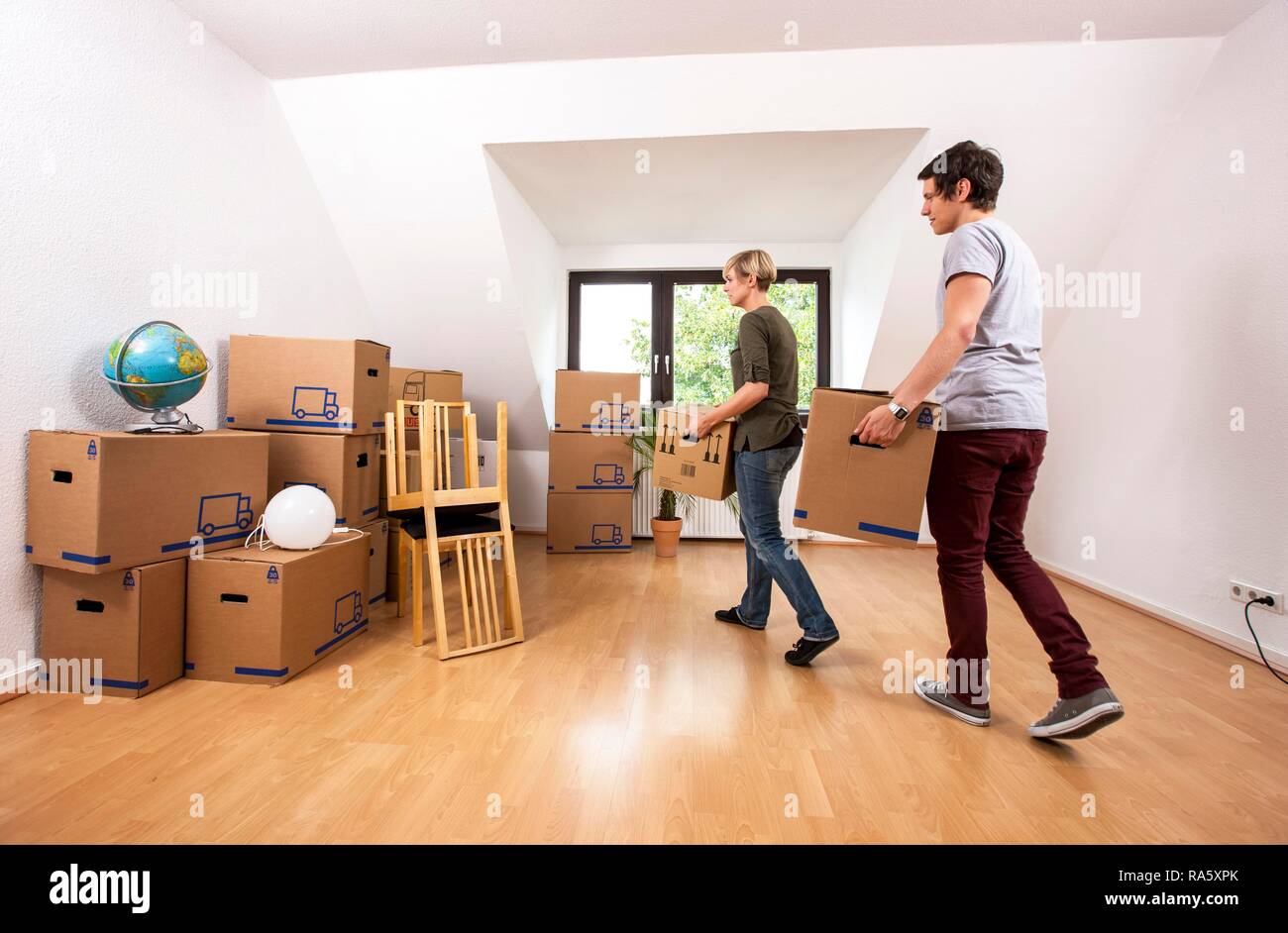 Young couple carrying moving boxes and furnishings into the empty room ...