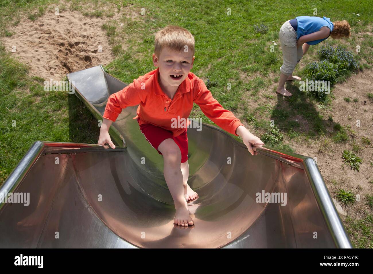 Boy climbing up a slide on a playground, Burgwallinsel island, Lake ...