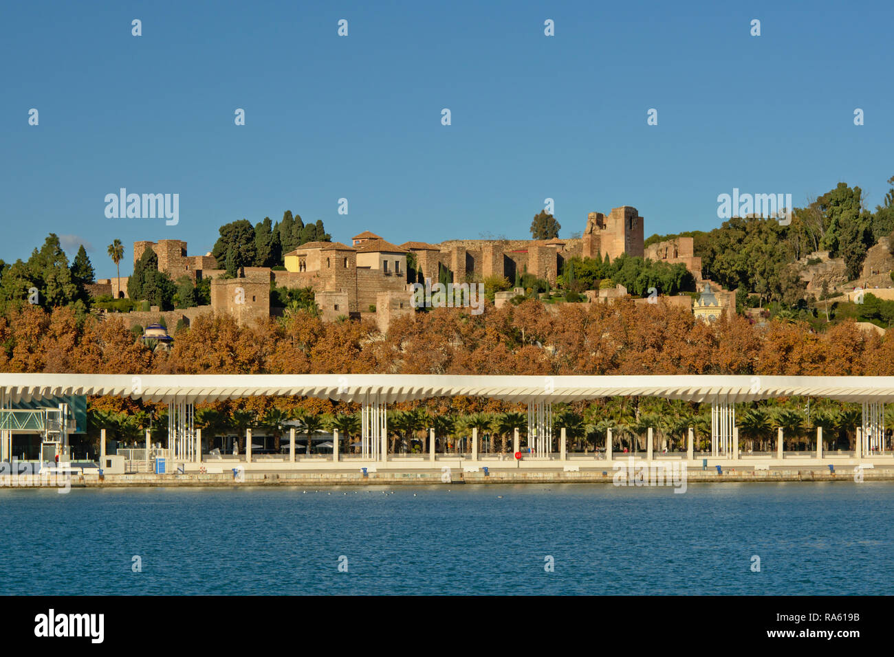 Paseo del muelle uno promenade with Alcazaba moorish castle on a hill ...