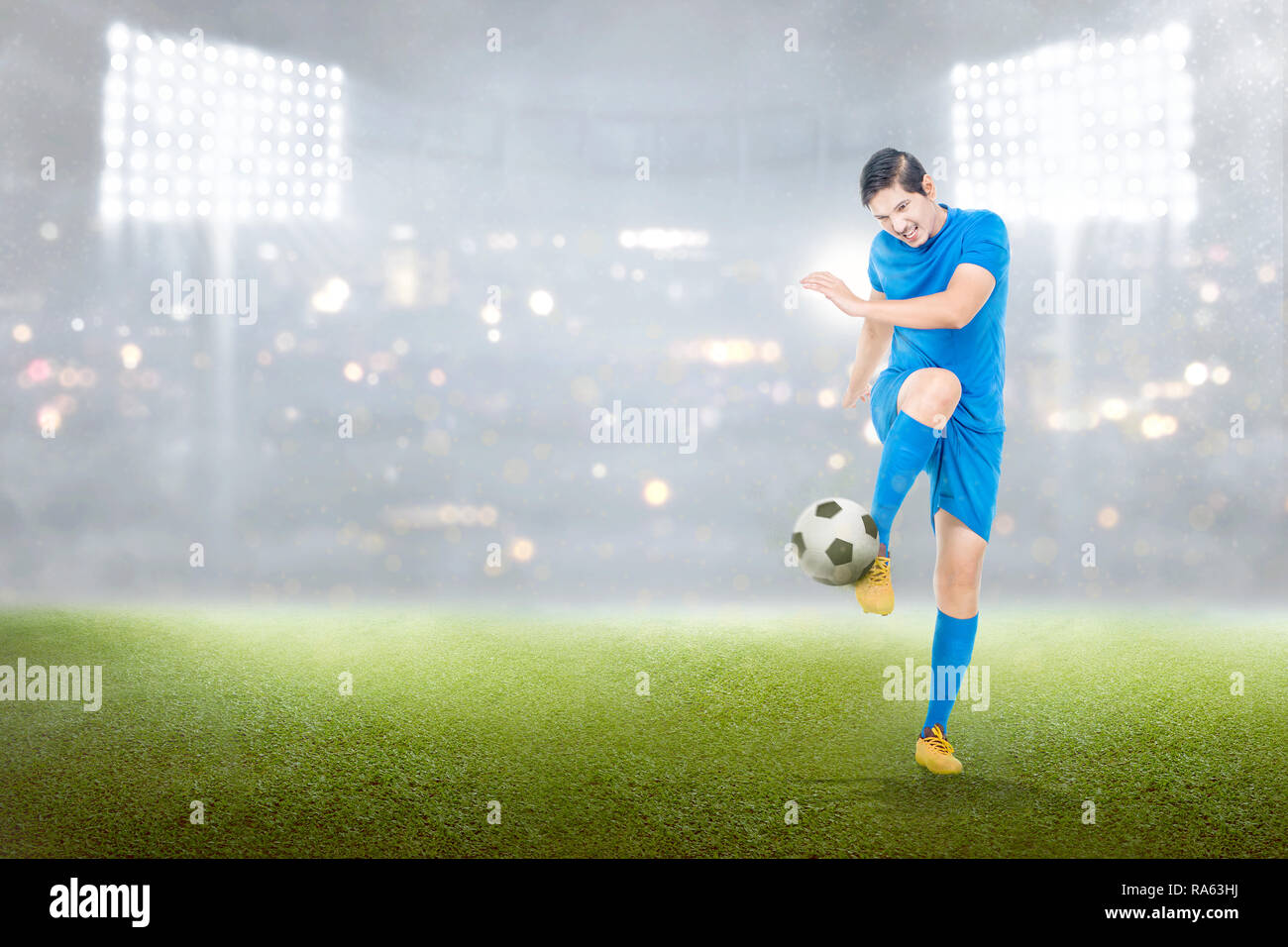 Handsome asian soccer player man in action with ball on stadium field ...