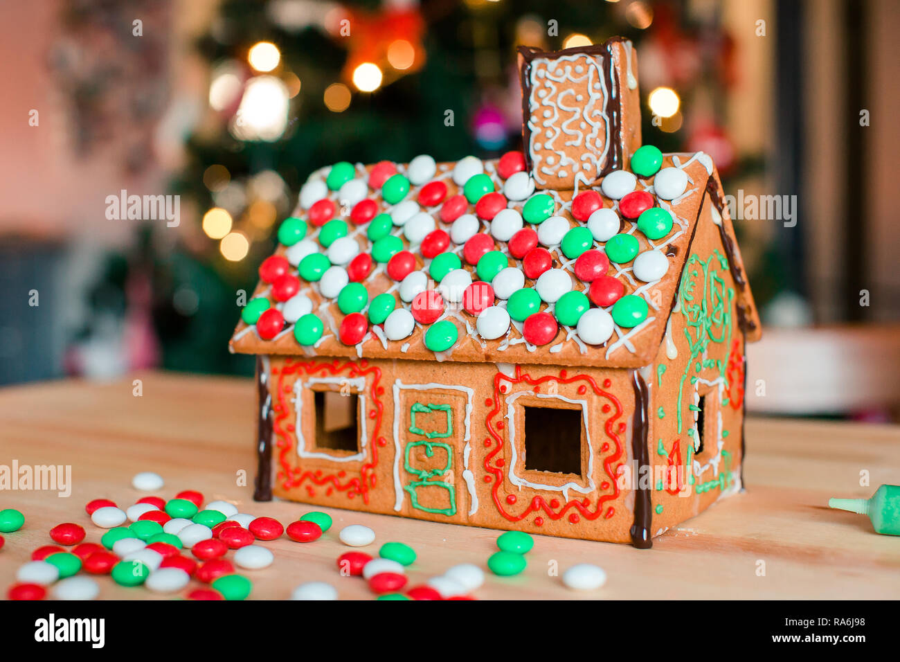 Homemade Christmas Gingerbread House on a table. Christmas tree lights ...