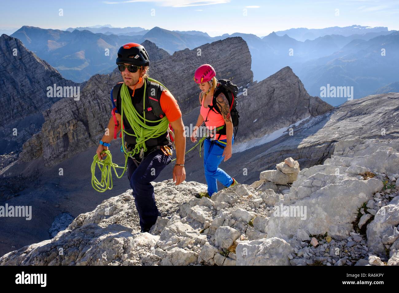 Mountain guide guiding a young woman on a short rope through a rock ...