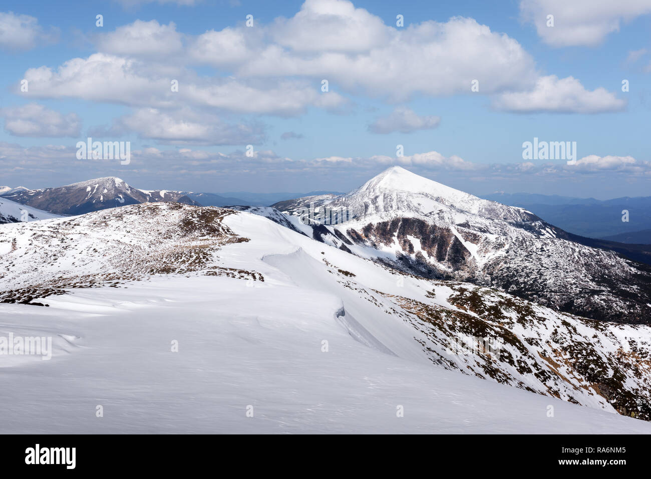 View of the stony hills with snow and blue sky. Dramatic spring scene ...