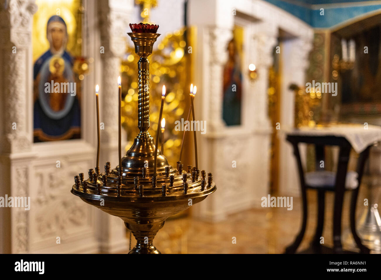 Many burning wax candles in the orthodox church or temple on golden ...