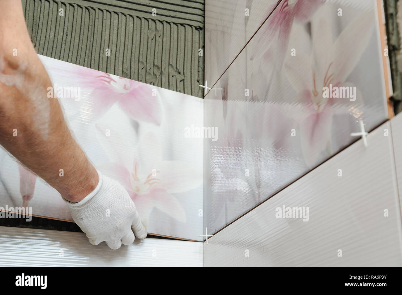 Installing the tiles on the wall. A worker putting tiles in the ...