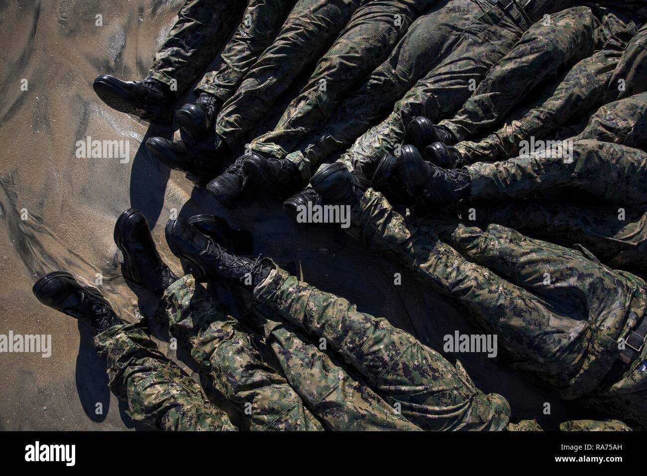 U.S. Navy SEAL candidates lay together as the tide rises during Basic ...