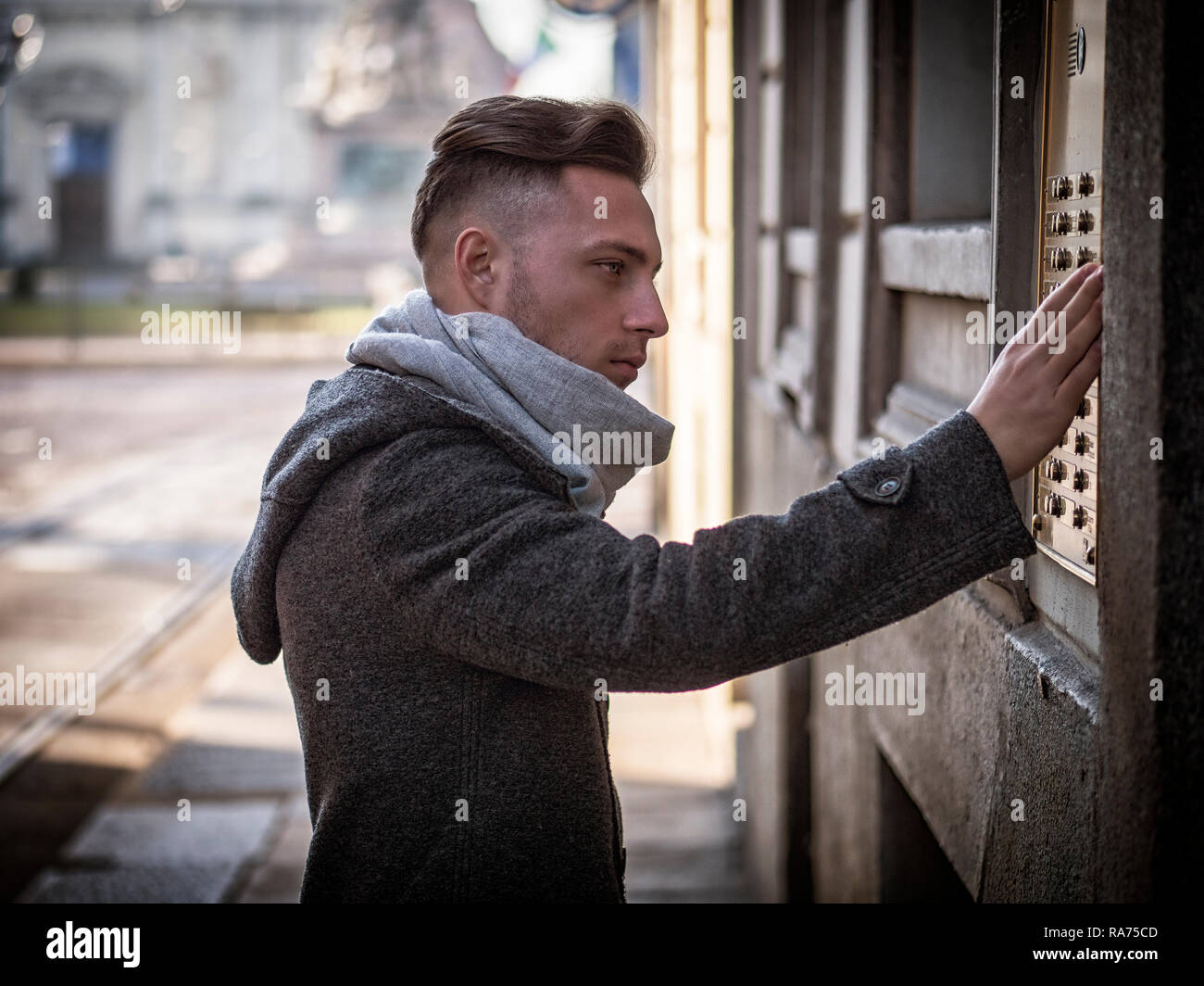 Handsome stylish young man ringing doorbell at building Stock Photo - Alamy