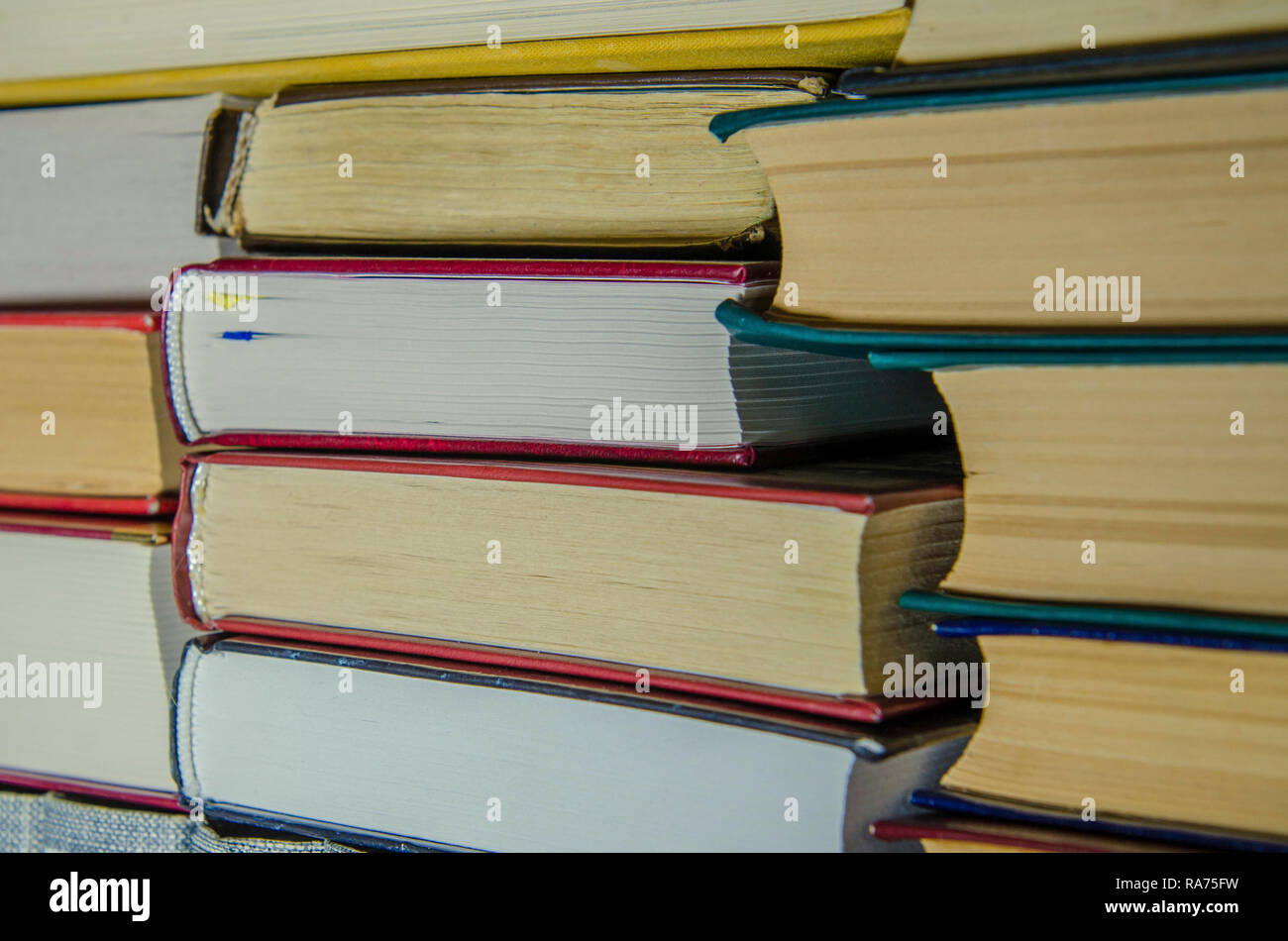 a stack of colorful books on the shelf in a library or a room close-up ...