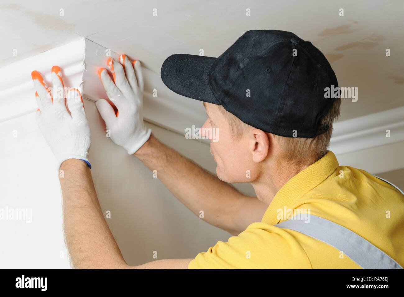 Installation of ceiling moldings. Worker fixes the plastic molding to ...