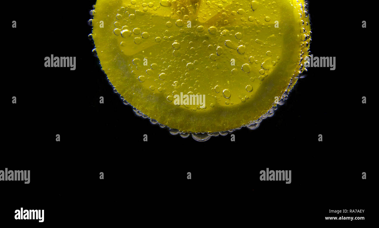 A slice of lemon with bubbles isolated on black background Stock Photo ...