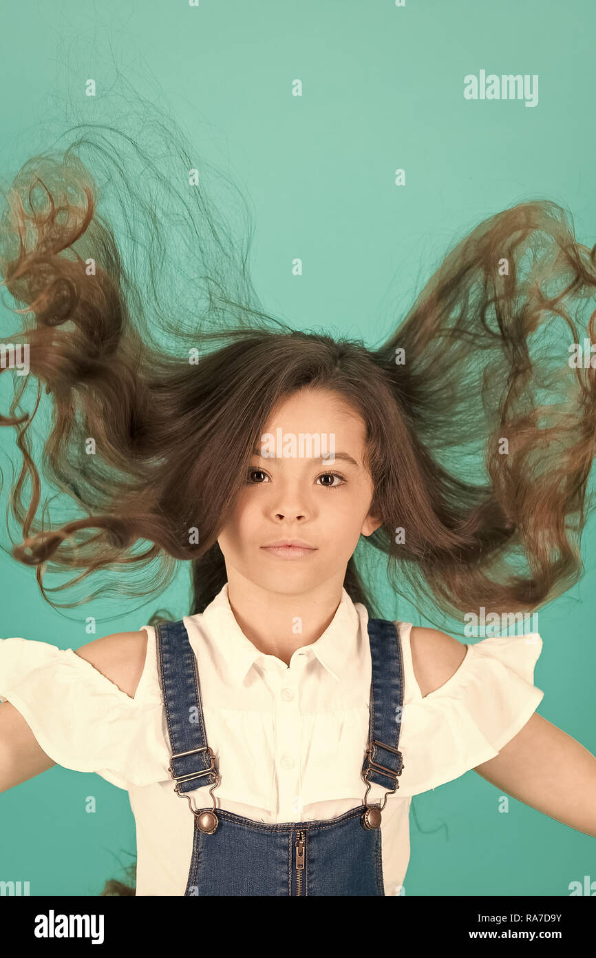 Child with long healthy hair. Girl with flying hair on blue background ...