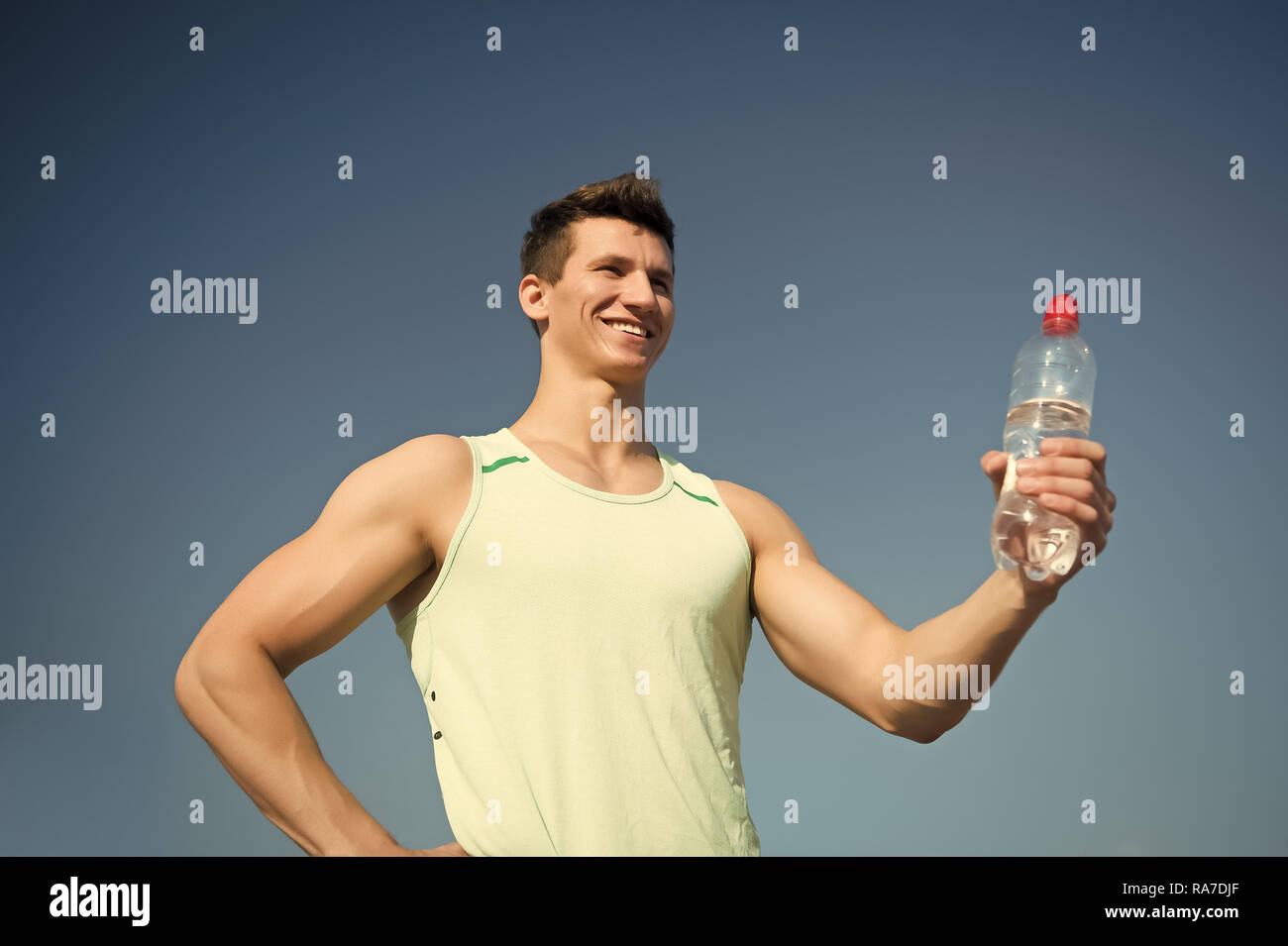 Happy man with water bottle in muscular hands. Bodybuilder with muscles ...