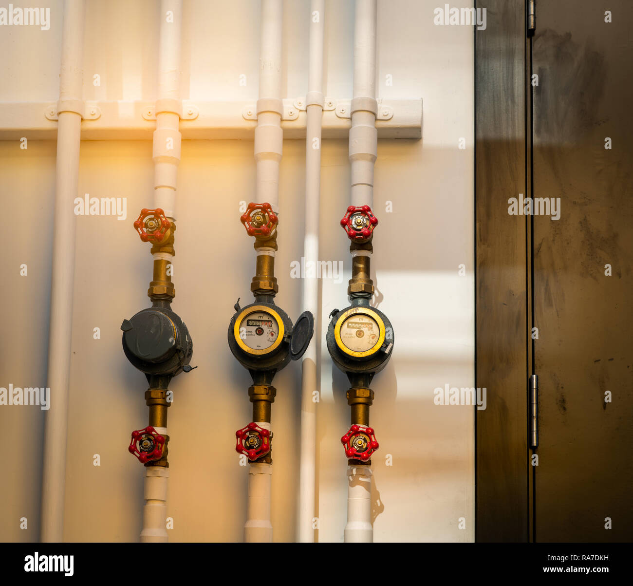 Single water meter and red valves on white concrete wall of house ...
