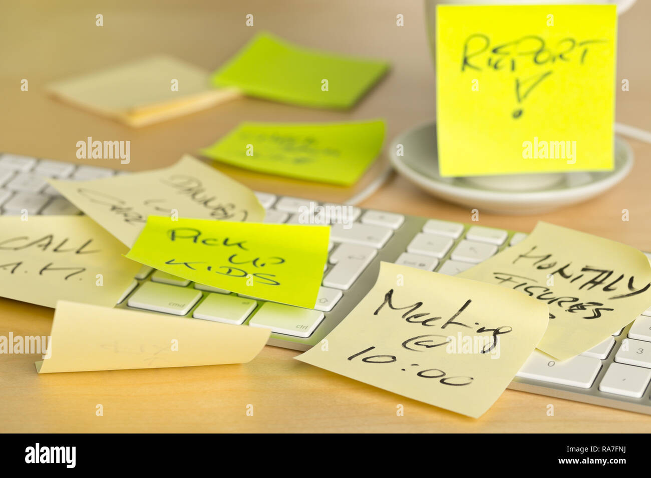 Computer keyboard and coffee cup covered with sticky notes with ...