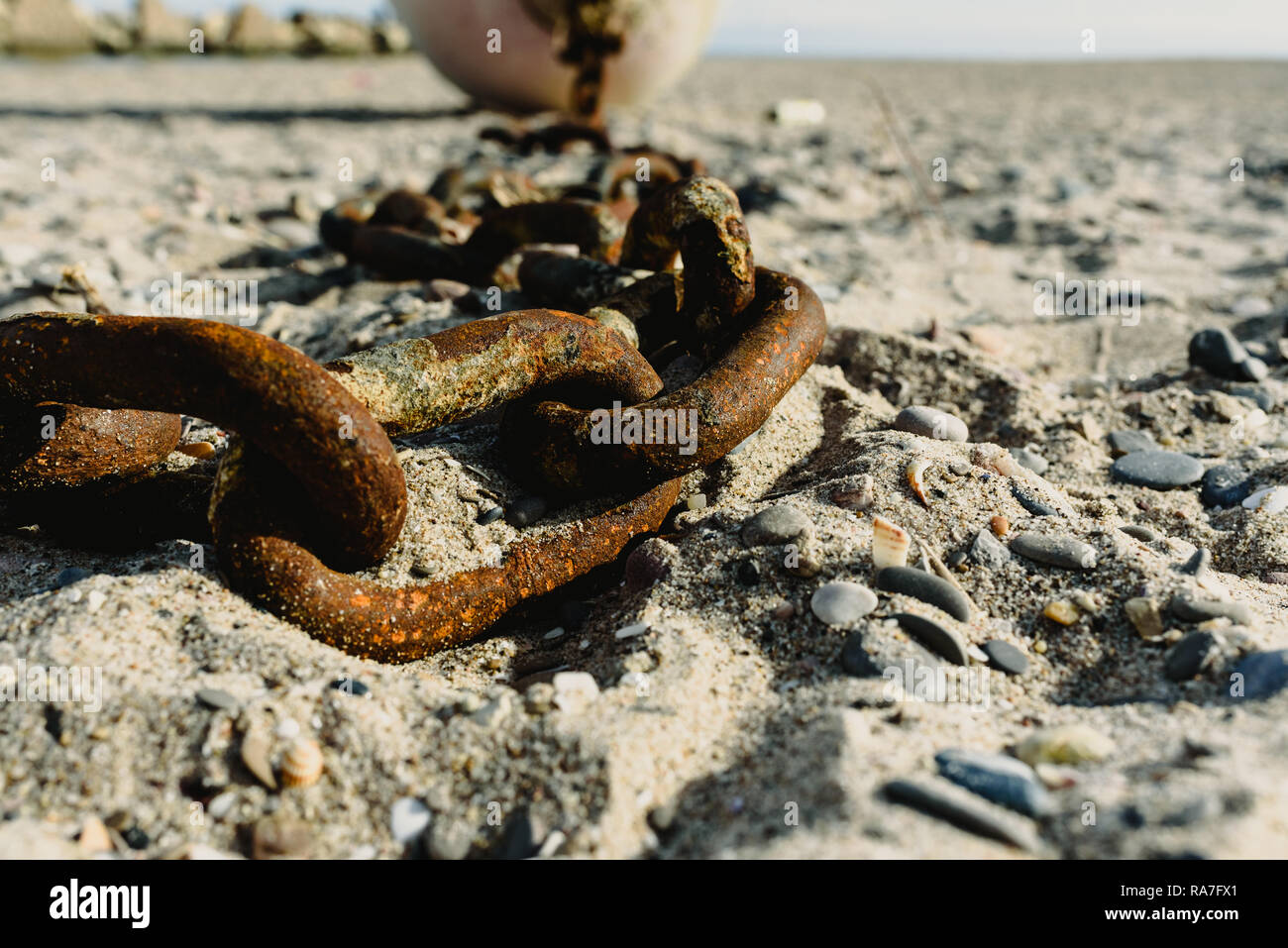 Concept of abandonment, old rusty and broken chains thrown in the sand ...