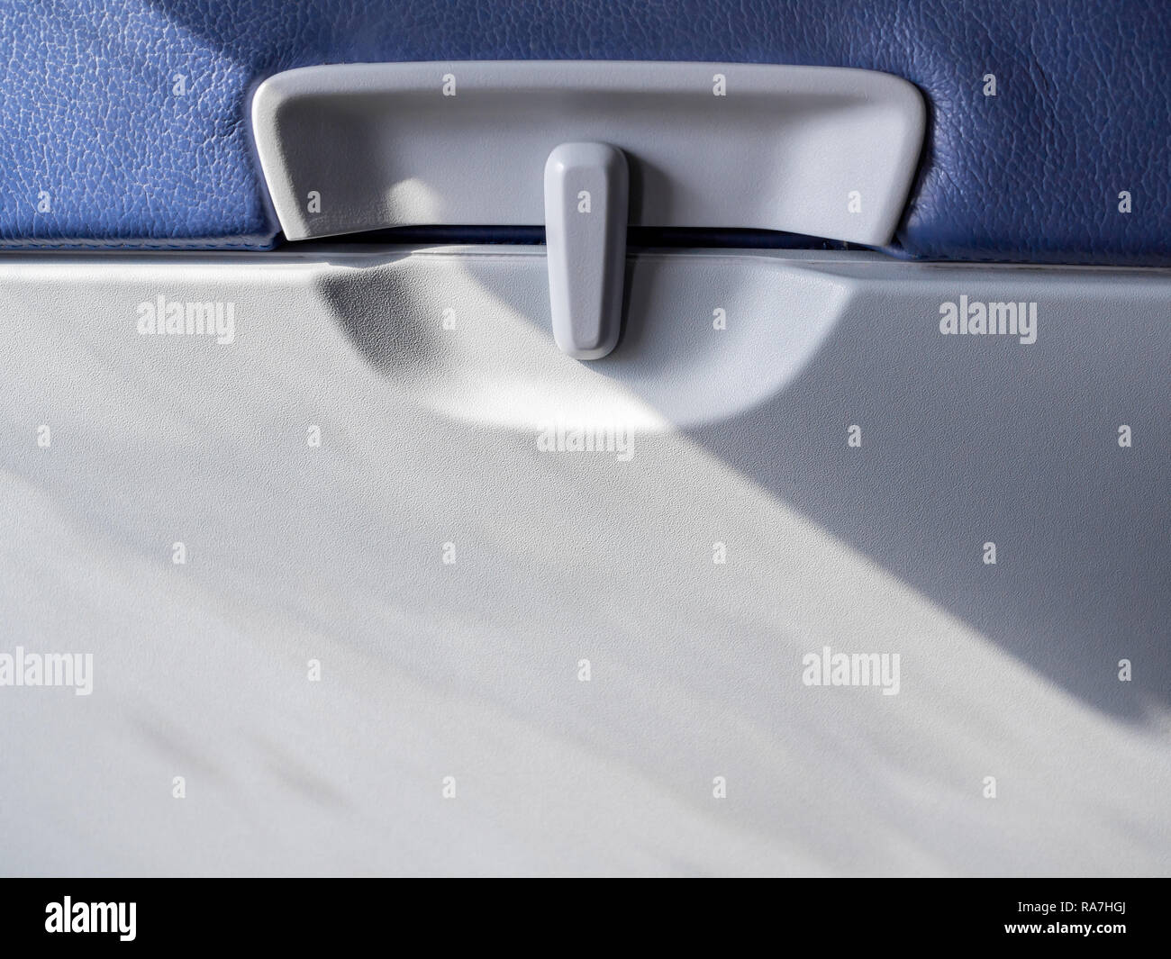 Close up lock of plastic food tray on the back of blue leather seats on ...