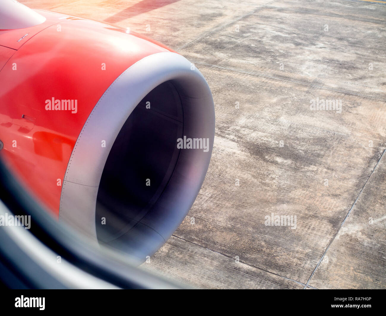 Jet engine of red airplane from window of passenger view on concrete ...