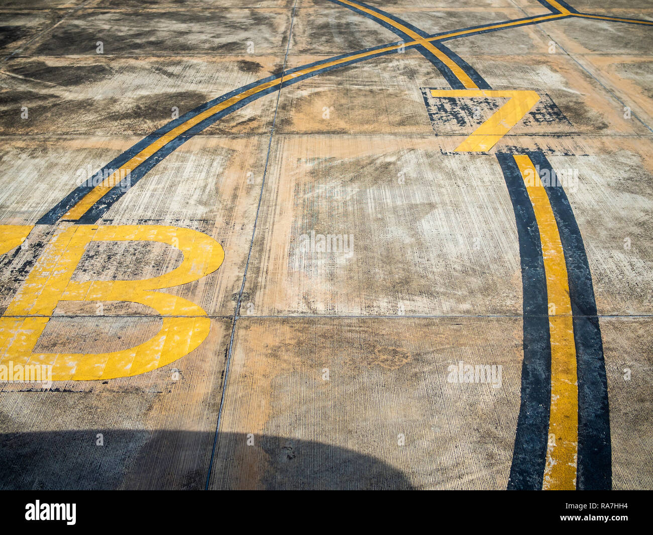 Yellow and black curved strips and code number on concrete runway in ...