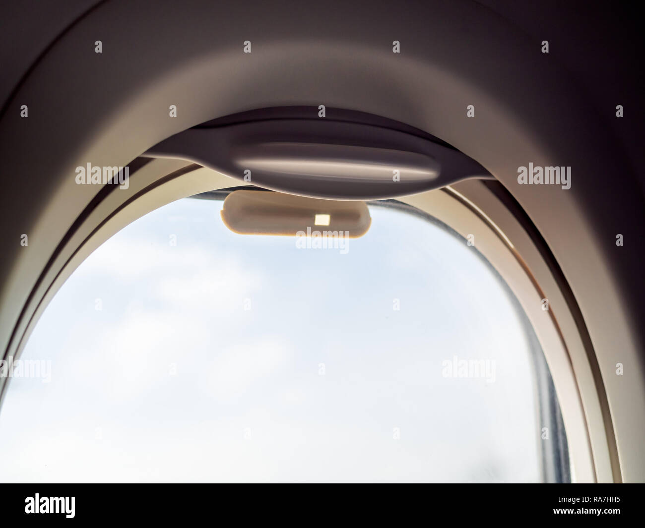 Close-up hand grip on airplane window in the dark cabin of airplane ...