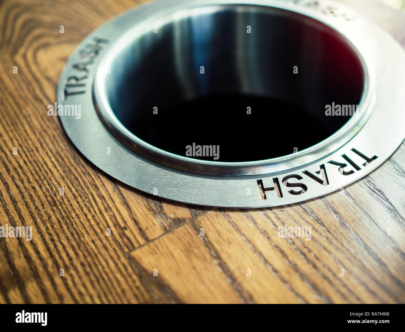 Close-up modern round trash bin hole on wooden background in coffee ...
