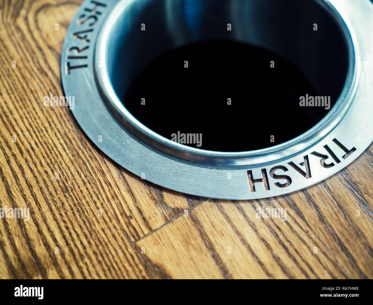 Close-up modern round trash bin hole on wooden background in coffee ...