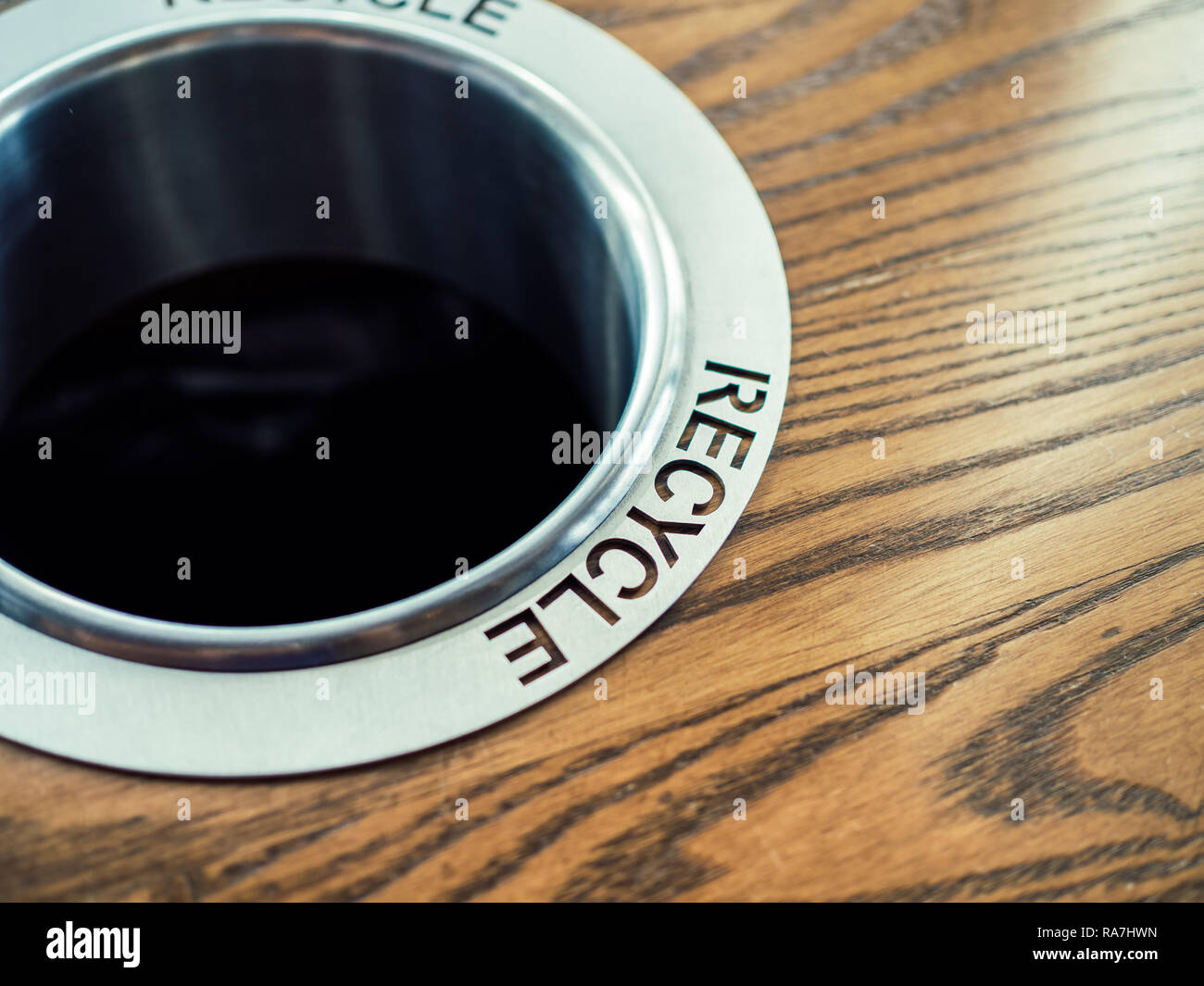 Close-up modern round recycle trash bin hole on wooden background in ...